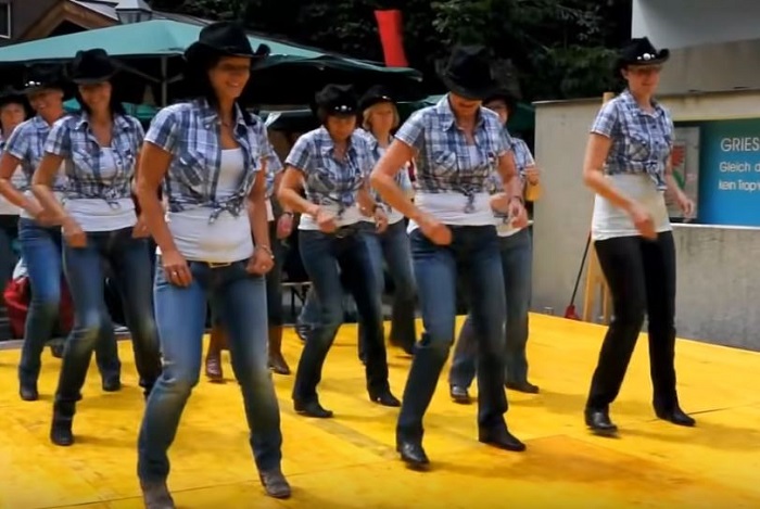 Dancers do lively line dance to classic country song