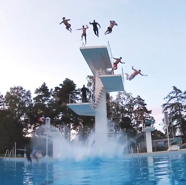 18 Men stand at the top of diving boards by pool, then leap in