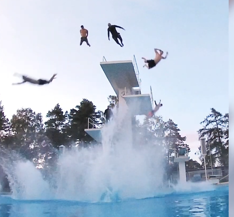 18 Men stand at the top of diving boards by pool, then leap in