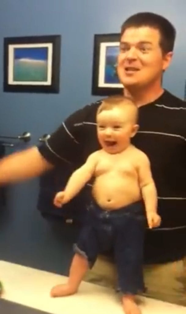 Strong baby flexes muscles making dad fall apart with laughter