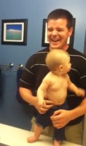 Strong baby flexes muscles making dad fall apart with laughter
