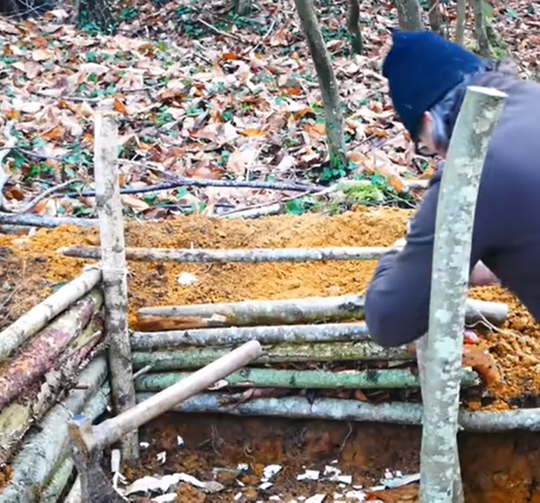 Bushcrafter shows how to build warming forest pit shelter with simple tools