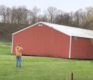 Group of Amish men pick up barn and carry it to new location with their ...