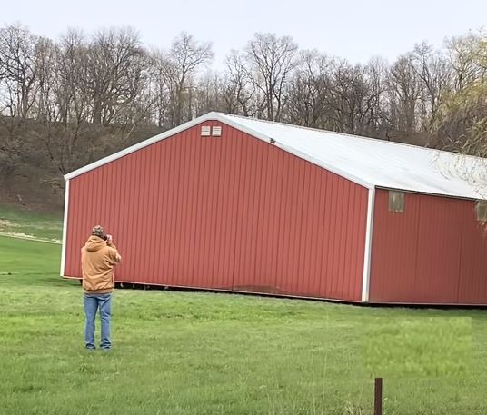 Group of Amish men pick up barn and carry it to new location with their ...