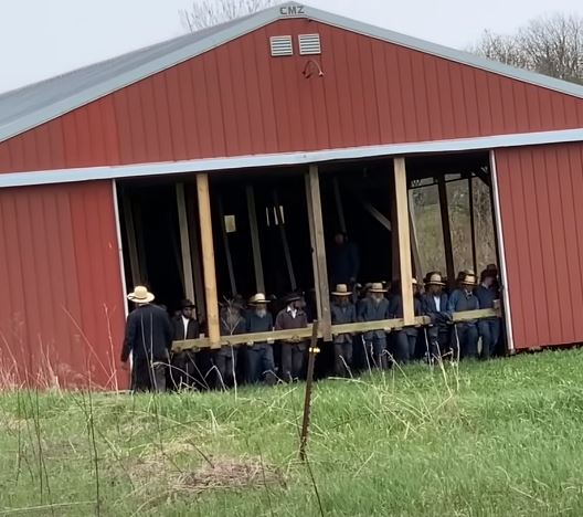 Group of Amish men pick up barn and carry it to new location with their ...