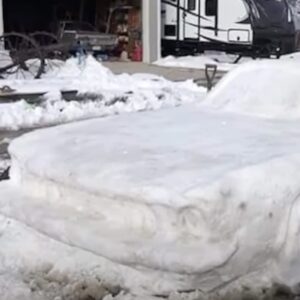 Officer stops to give “ticket” to what appears to be a snow-covered Mustang